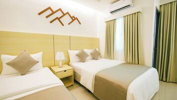 Quarto de hotel com duas camas, um painel de cabeceira de madeira, uma mesa de cabeceira com abajur e uma janela com cortinas.