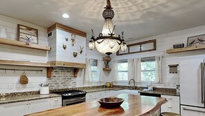 Cozinha moderna com ilha central, eletrodomésticos de aço inoxidável e decoração na parede.