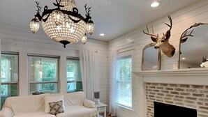 Uma sala de estar aconchegante com um sofá branco, um candelabro, uma lareira e chifres de veado na lareira.