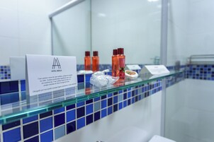 Uma área de recepção de hotel com um balcão de vidro, uma placa com o logotipo do hotel e amenities de banho.
