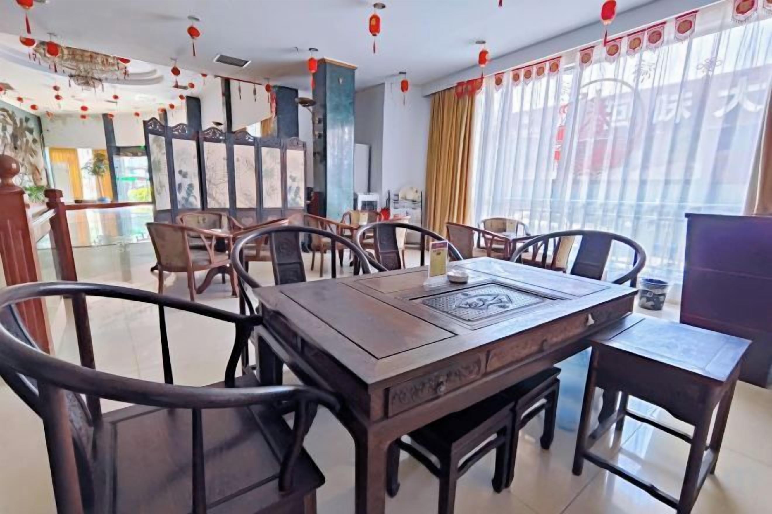 Uma sala de jantar tradicional com mesa e cadeiras de madeira, um biombo decorativo e vista pela janela com cortinas.