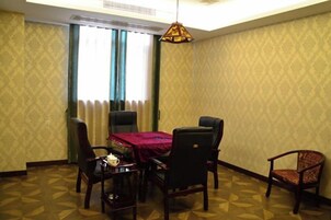 Uma área de refeições com mesa e cadeiras, papel de parede estampado e um lustre.
