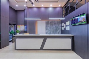 Uma área de recepção moderna com balcão, tela digital e quadros com certificados na parede.