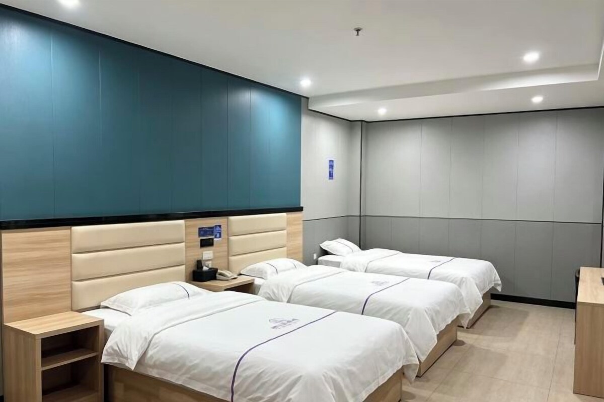 Quarto de hotel com duas camas, uma escrivaninha e um guarda-roupa.