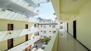 Um edifício com várias andares, varandas, teto de vidro e plantas em vasos.