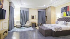 Quarto de hotel moderno com uma cama grande, uma escrivaninha e uma cadeira. Há uma televisão de tela plana na parede.