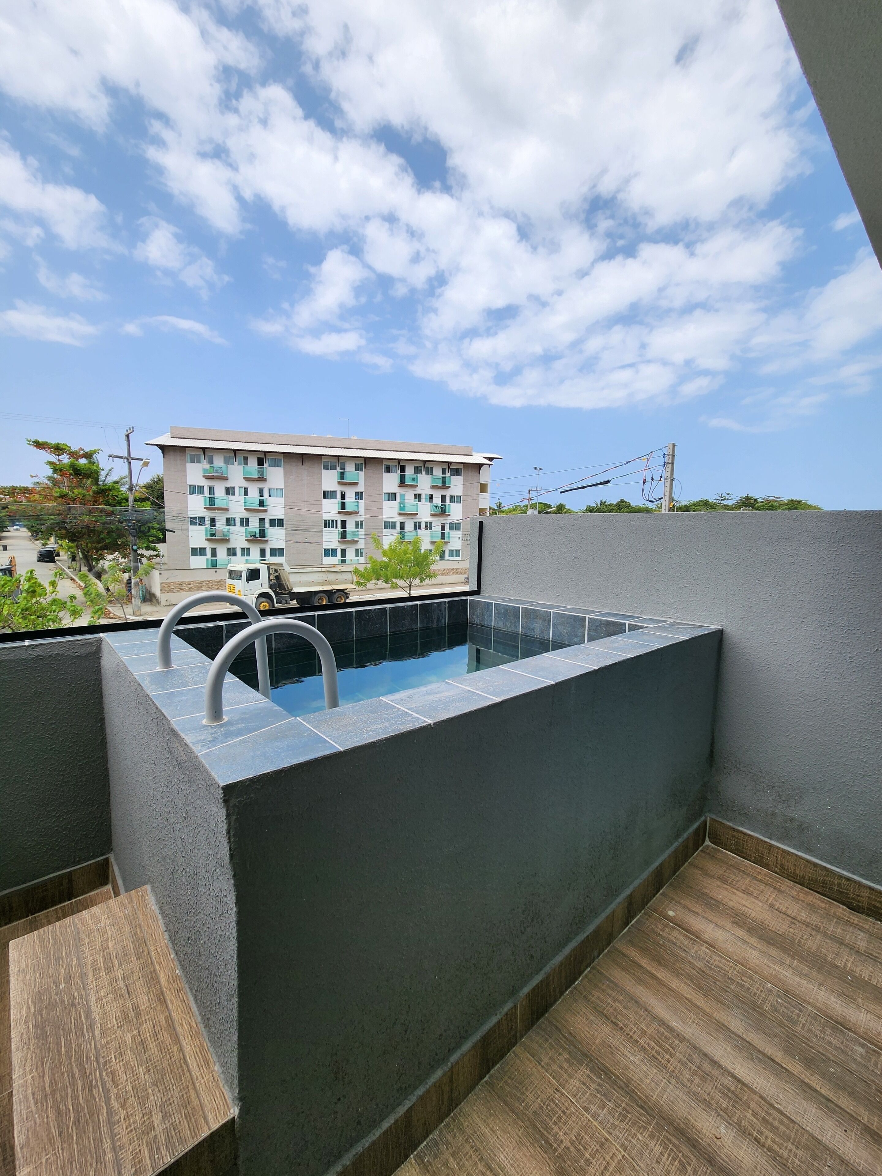 Uma piscina no terraço com vista para um edifício alto ao fundo.