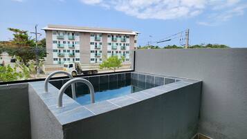 Uma piscina no terraço com vista para um edifício alto ao fundo.