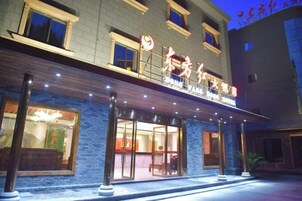 Hotel com entrada notável, área externa coberta e placa visível com caracteres chineses.