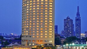 Um hotel moderno com fachada curva, vários andares e janelas iluminadas.