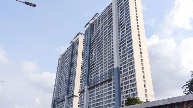 Um edifício alto com design arquitetônico moderno, destacando uma grade de janelas e uma estrutura vertical imponente no centro.