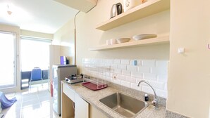 Cozinha moderna com pia de aço inoxidável, backsplash de azulejos brancos e bancada com escorredor de louça.