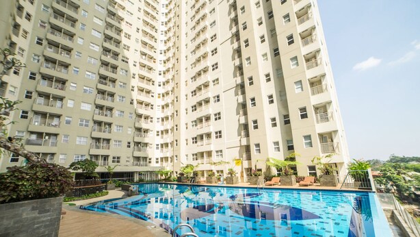 Um edifício residencial alto com uma piscina em primeiro plano.
