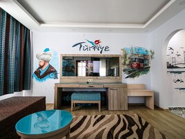 Uma sala de estar com TV, sofá, mesa de centro e uma parede com um mural.