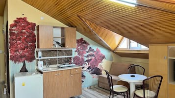Uma cozinha compacta com armários de madeira, pia e área de jantar com cadeiras.