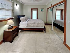 Um quarto com uma cama, mesa de cabeceira, luminária, cômoda e um espelho grande.