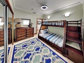 Quarto com uma cama beliche, cômoda, espelho e tapete estampado.