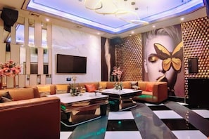 Uma área de estar moderna com sofás de couro, uma TV de tela plana e um painel de parede estampado.