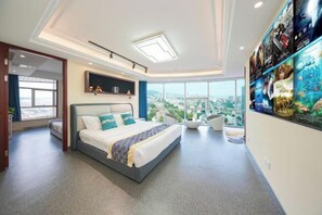 Quarto de hotel moderno com uma cama grande, vista para a cidade e parede com pôsteres de filmes.