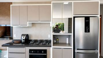 Cozinha moderna com fogão embutido, forno e geladeira de aço inoxidável.