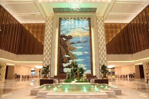 Um hall espaçoso com um grande mural, uma fonte e iluminação moderna.