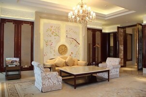 Uma sala de estar ampla com um grande candelabro, um conjunto de sofás e uma mesa de centro.
