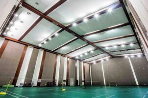 Um amplo espaço interior com teto alto, várias luminárias e piso verde.