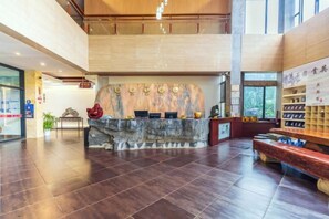 Um lobby amplo com uma mesa de recepção, uma parede de pedra e uma área de estar.