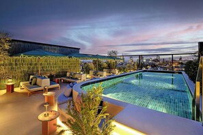 Uma área de piscina no terraço com assentos de lounge e vista para a cidade.