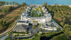 Vista aérea de um resort com um edifício central, uma piscina e uma praia.