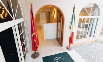 Entrada de hotel com balcão de recepção, área de espera e vista do interior.