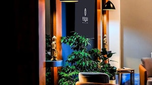 Um interior moderno com um sofá em tons escuros, uma planta em vaso e uma placa na parede.