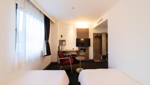 Quarto de hotel com duas camas, uma secretária com cadeira, televisão e uma mesinha.