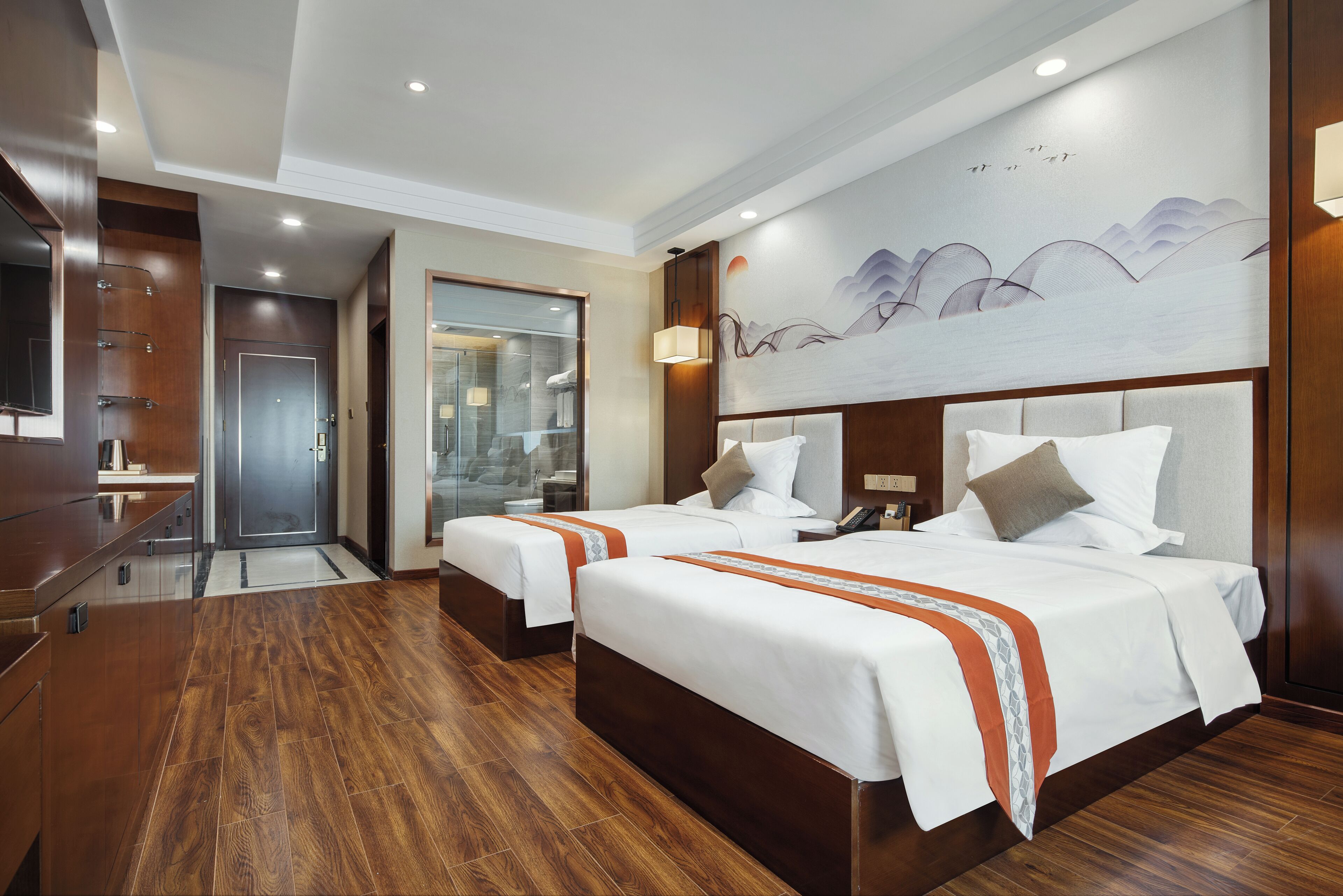 Quarto de hotel com duas camas, piso de madeira, uma pintura grande na parede e um banheiro visível através de uma porta de vidro.