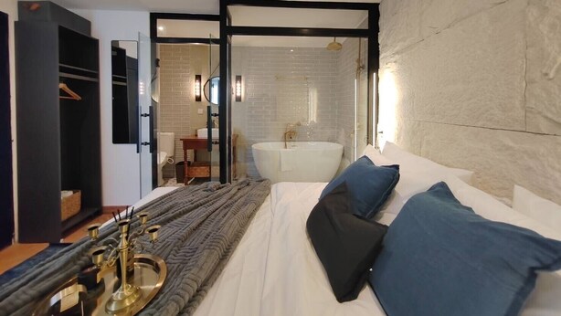 Quarto moderno com cama grande, banheira integrada e closet espaçoso.