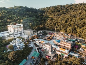 Vista aérea de uma cidade com mistura de edifícios modernos e tradicionais, rodeada por uma floresta densa.
