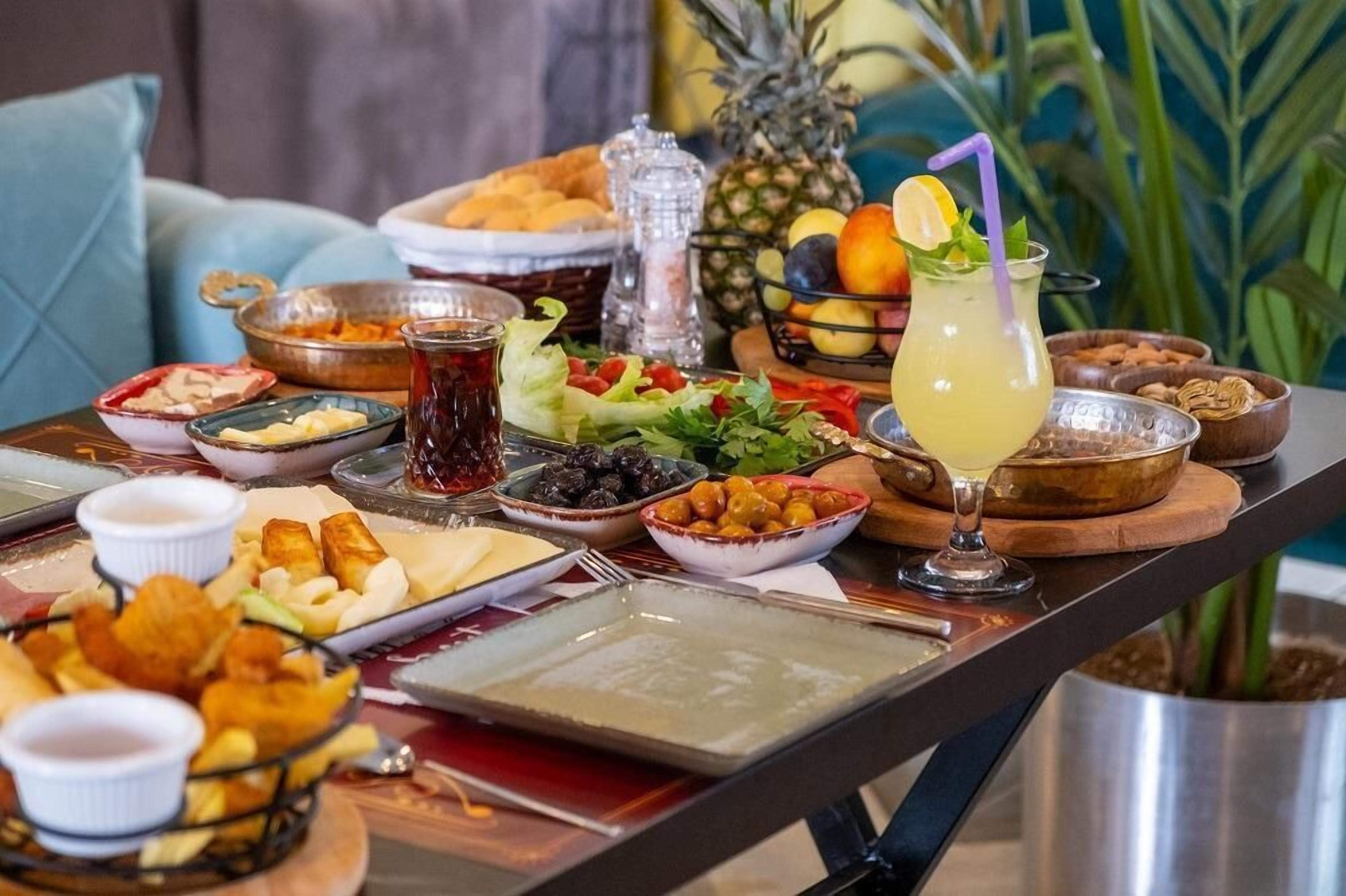 Uma mesa com diversos alimentos, incluindo frutas, vegetais e uma bebida com canudo.