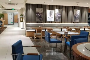 Um restaurante moderno com cabines e mesas, uma área de balcão e um espaço de estar com cadeiras azuis.