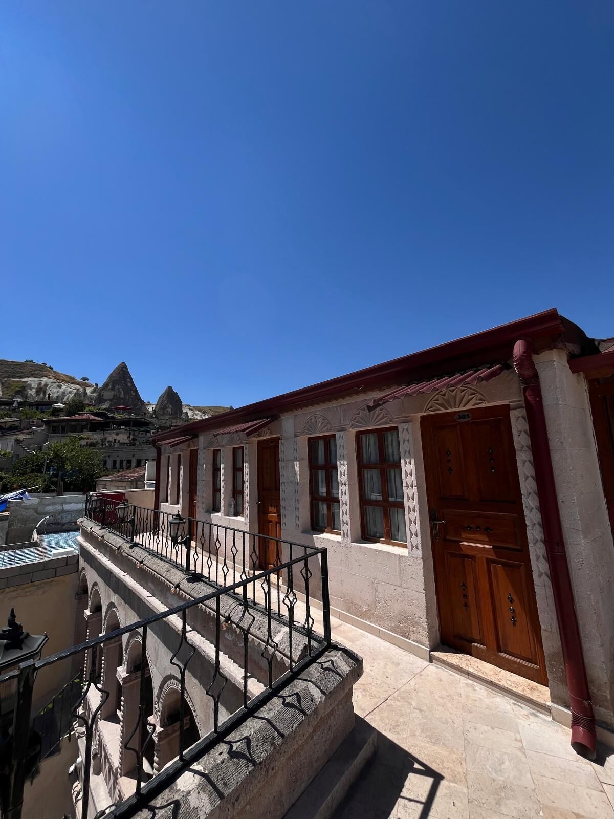Um edifício com varanda, porta de madeira e vista da região ao redor.