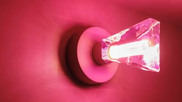 Uma luminária rosa com design geométrico em uma parede vermelha.