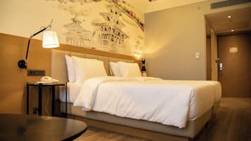 Quarto de hotel com cama, luminária de cabeceira e um mural na parede.