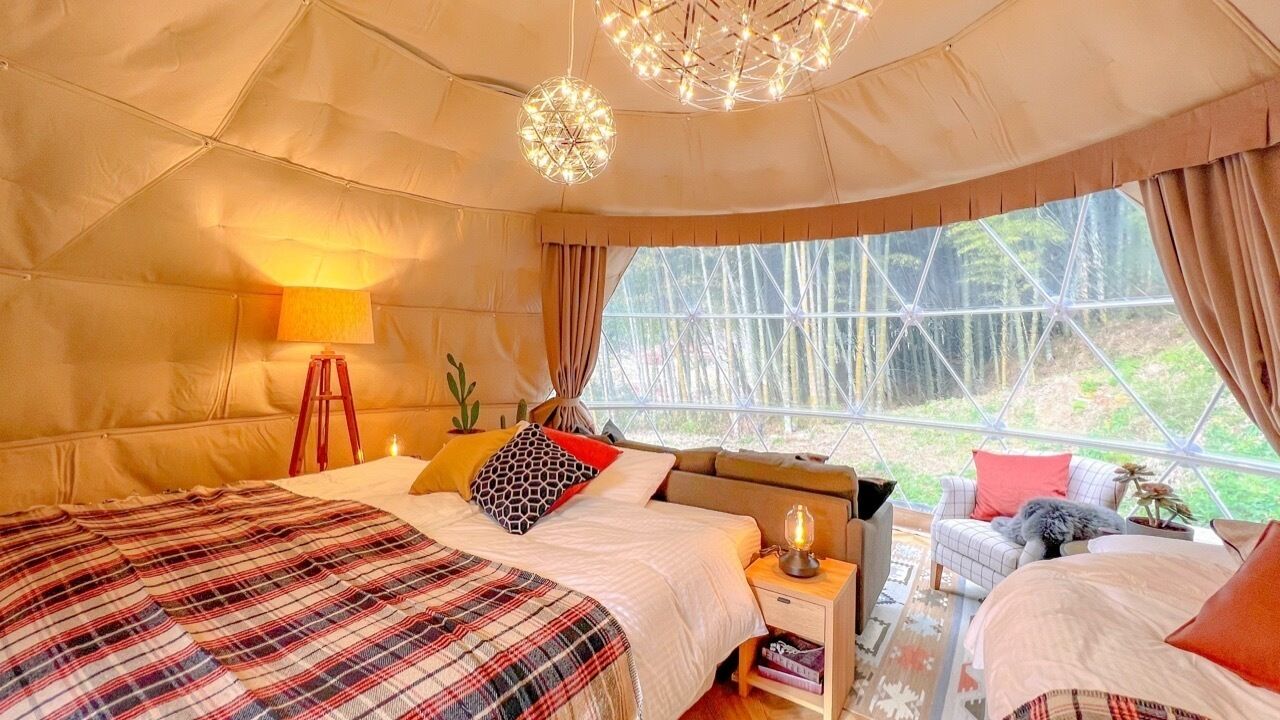 Um interior acolhedor com uma cama grande, uma cama menor, uma mesa de cabeceira e uma janela com vista para o verde.