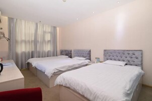 Quarto de hotel com duas camas, uma escrivaninha e uma cadeira.