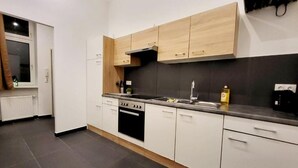 Cozinha moderna com armários brancos, forno preto, pia de aço inoxidável e bancada preta.