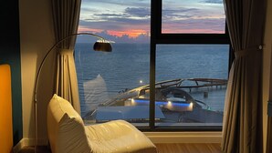 Quarto com uma grande janela para um pôr do sol e uma ponte.