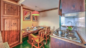 Uma cozinha com armários de madeira, uma mesa de jantar com cadeiras, um lustre e uma pia.