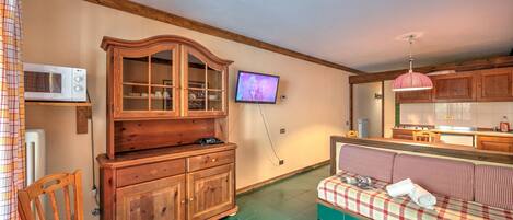 Uma sala de estar aconchegante com um armário de madeira, uma televisão, um sofá e uma mesa de jantar.
