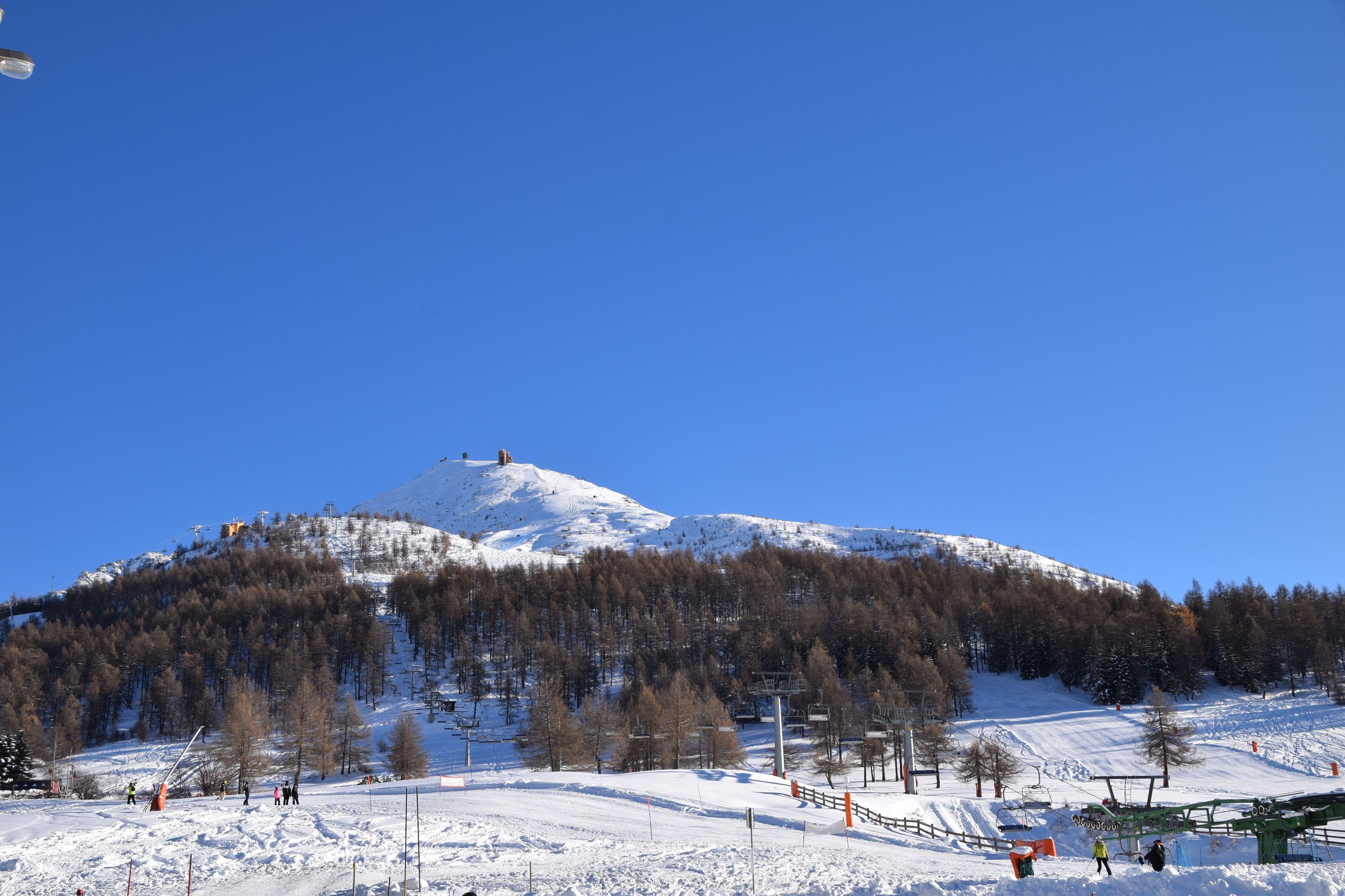 Montanha coberta de neve com um teleférico e um céu azul límpido.