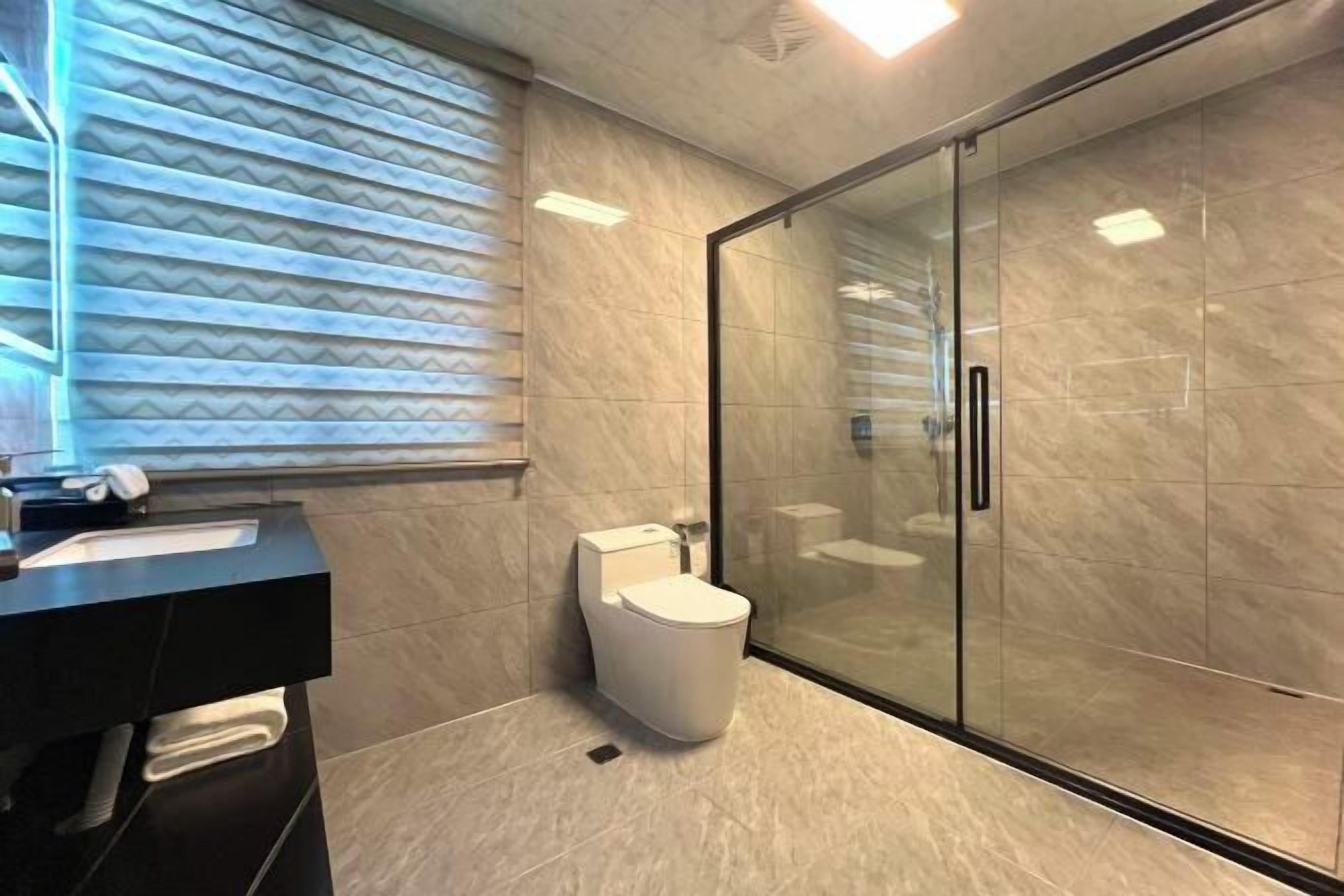 Uma casa de banho moderna com sanita, cabine de duche em vidro e lavatório com porta-toalhas.