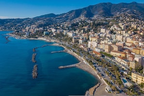 Paisagem urbana costeira com uma praia extensa e quebra-mares rochosos.